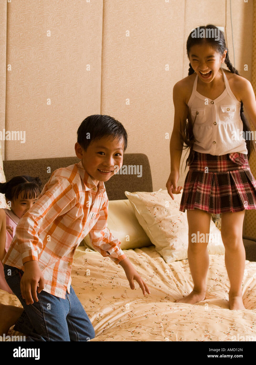 Three children jumping on bed laughing Stock Photo - Alamy