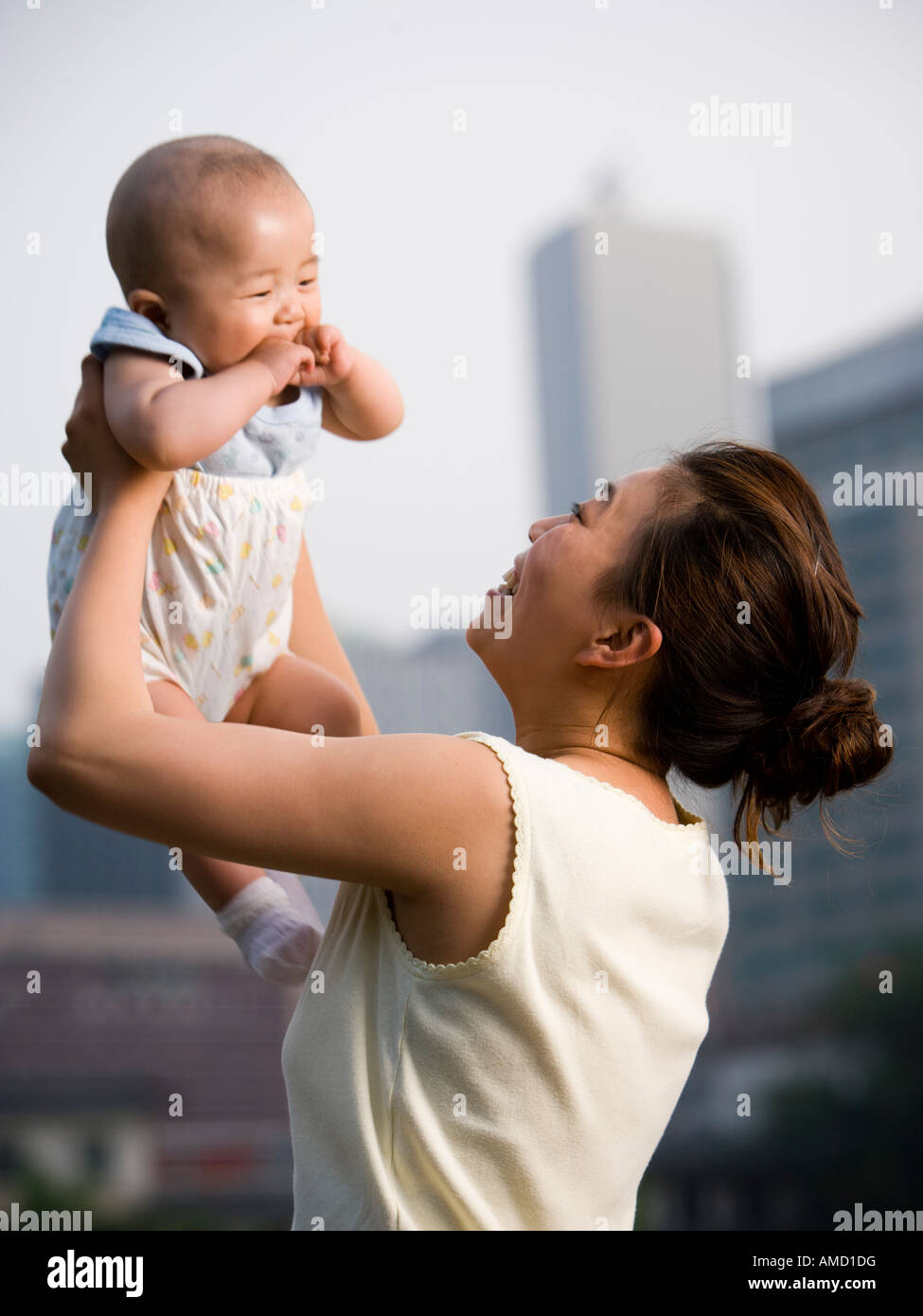 Woman lifting baby outdoors and smiling Stock Photo - Alamy