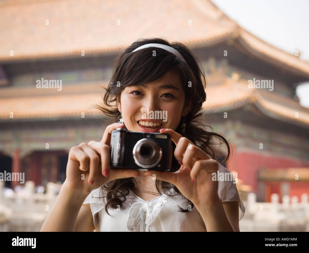 Teenage girl taking photograph outdoors with pagoda in background Stock Photo - Alamy