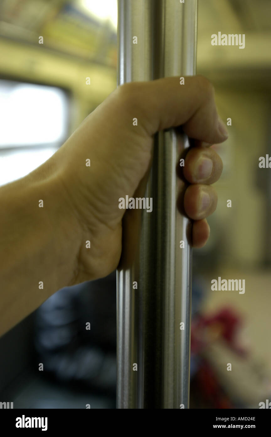 Hand holding upright handrail post in subway train Stock Photo - Alamy