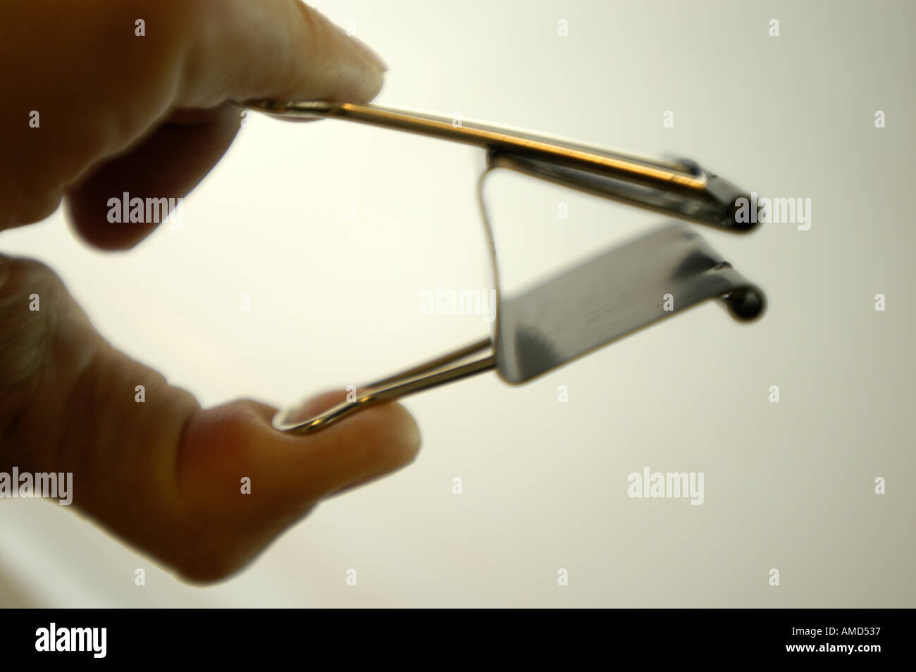 Hand pinching metal plastic clip side view white bkgrnd Stock Photo - Alamy