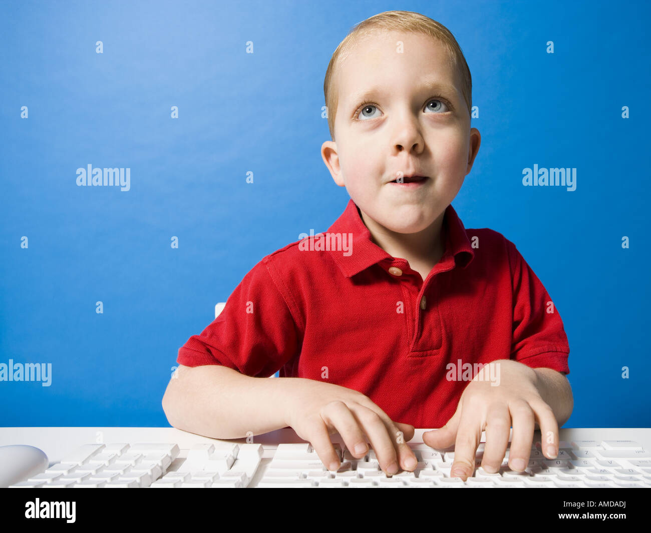 Boy typing at keyboard looking up Stock Photo - Alamy