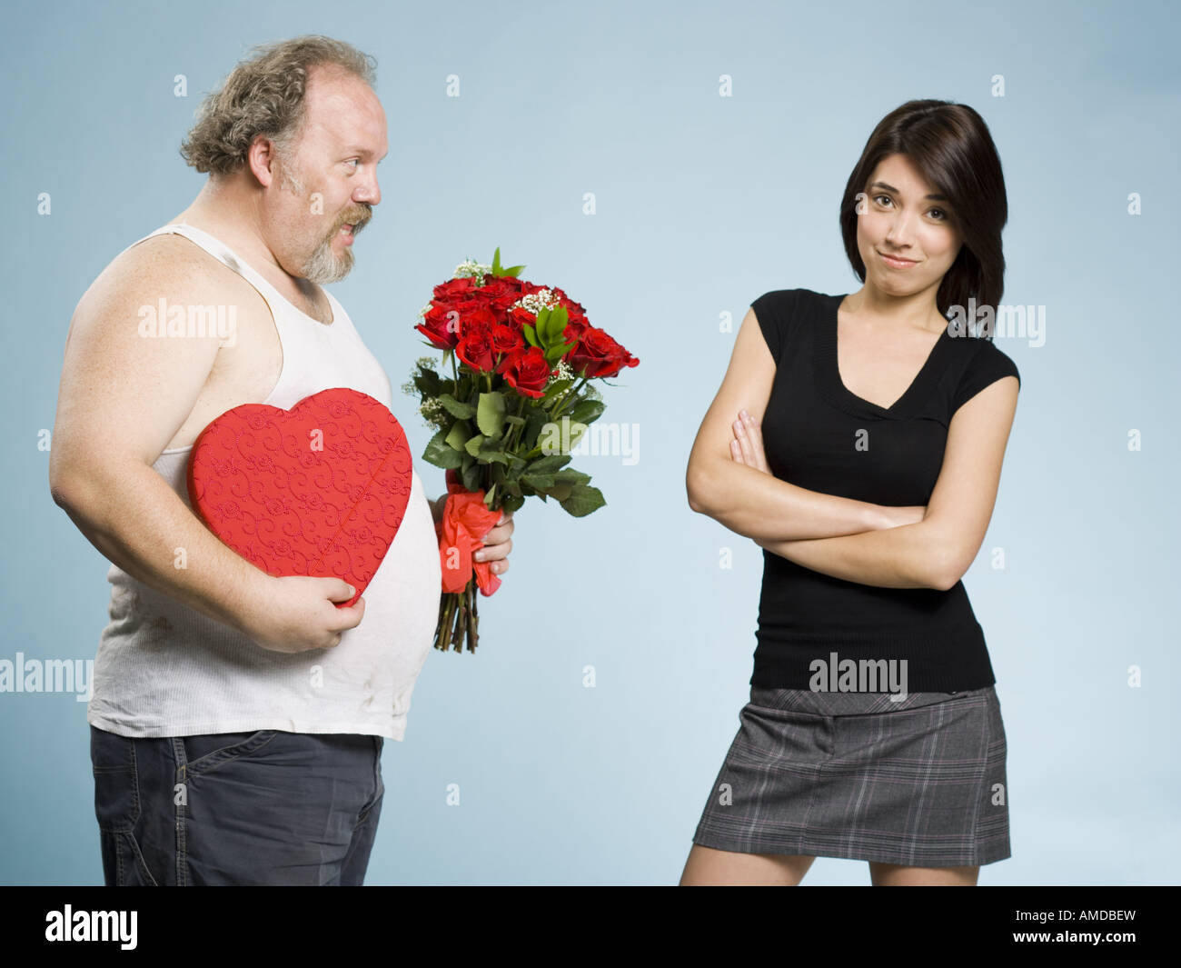Disheveled man with heart box and red roses with disinterested woman ...