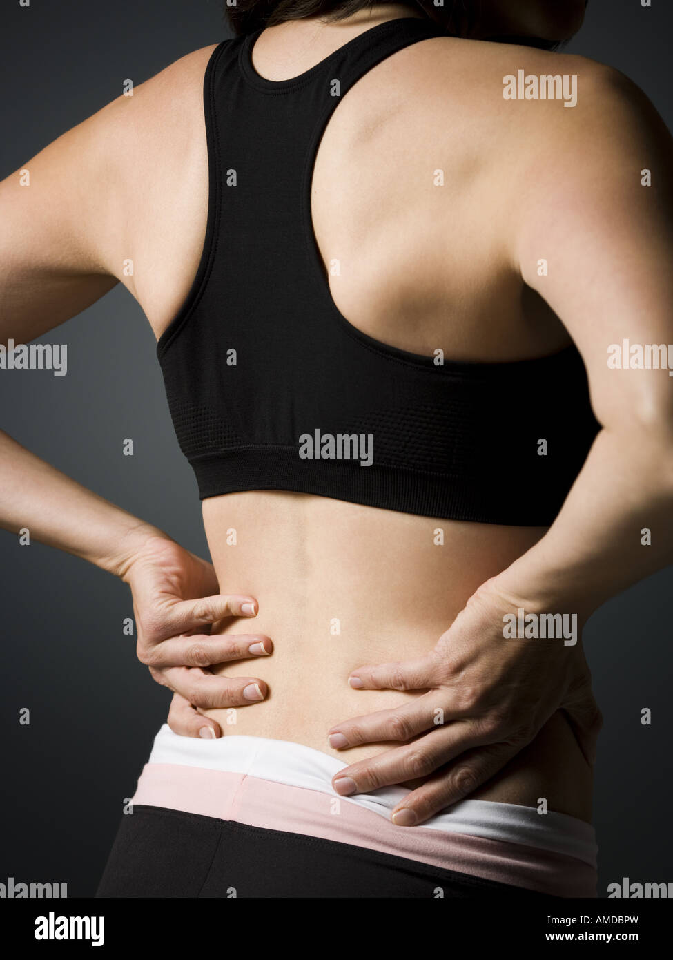 Rear view of woman with hands on lower back Stock Photo - Alamy