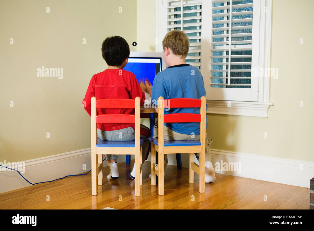 Rear view of two boys operating computer Stock Photo - Alamy