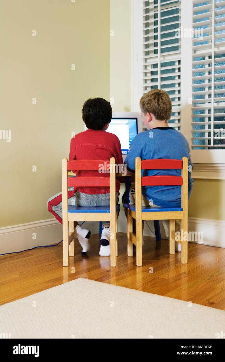 Rear view of two boys operating computer Stock Photo - Alamy