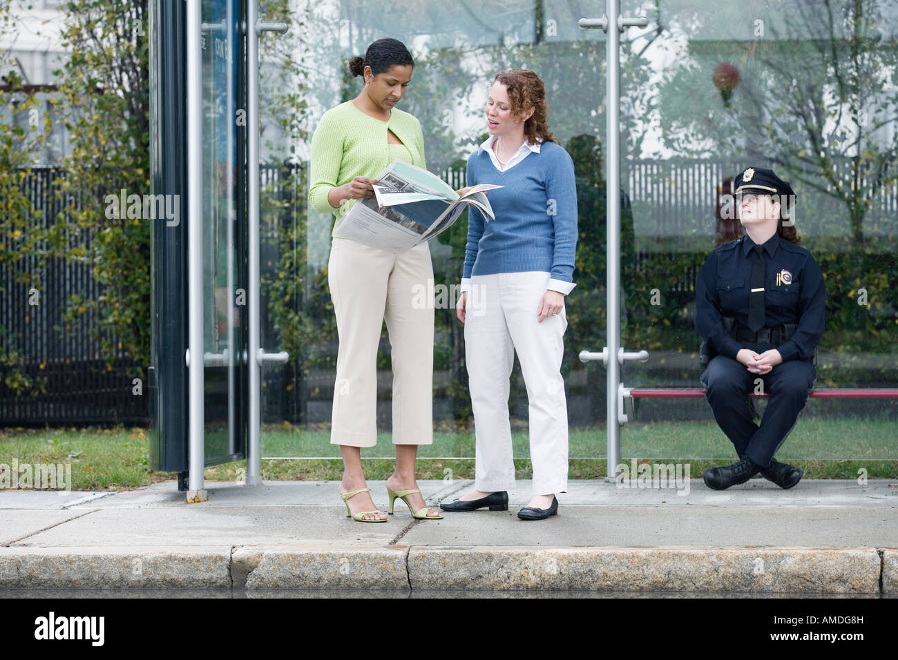 A female police officer watching while two women reading newspaper at a ...