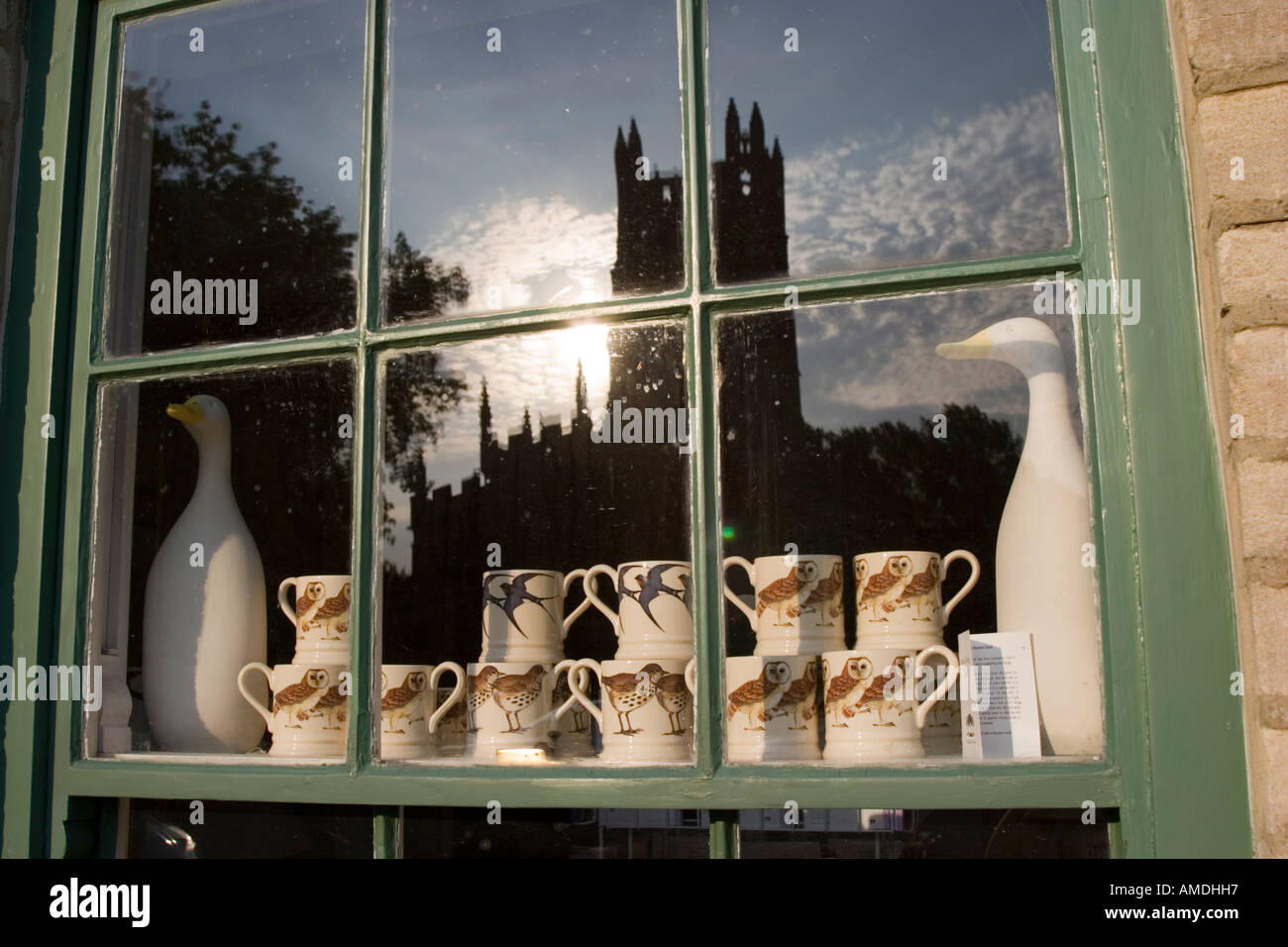 China cups and plates on display in shop window with church reflected ...