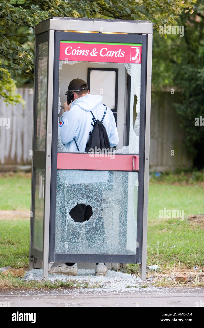 Man attempting to use a smashed and vandalised telephone box Stock ...
