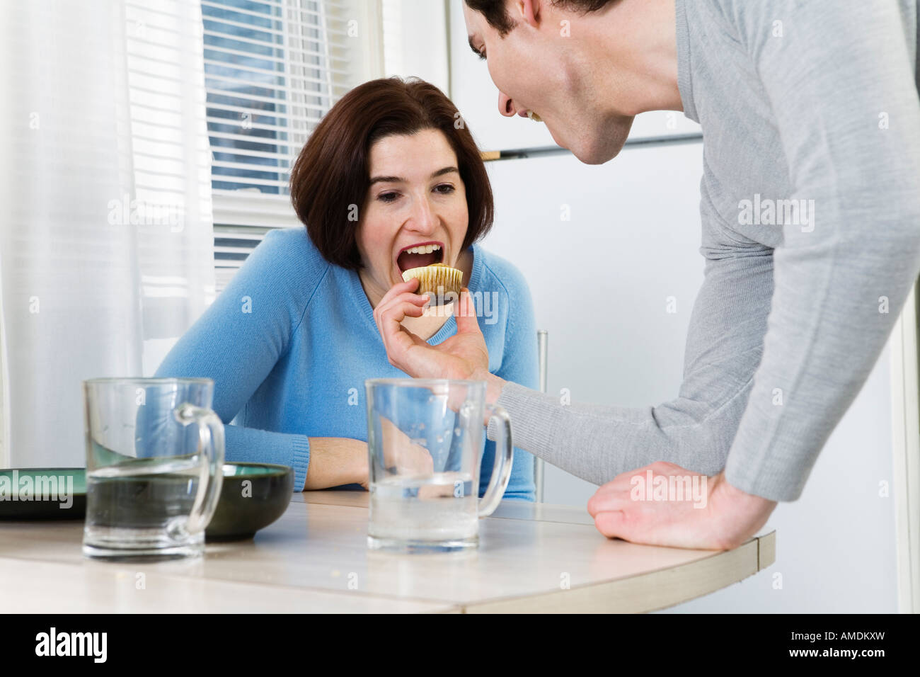 View of a mid adult couple eating muffin at the dining table Stock ...