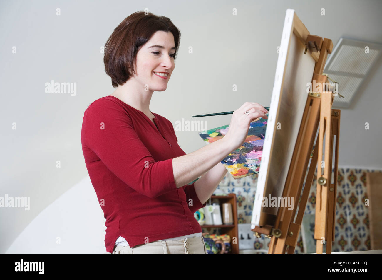 Side view of a smiling young woman painting using a brush Stock Photo ...