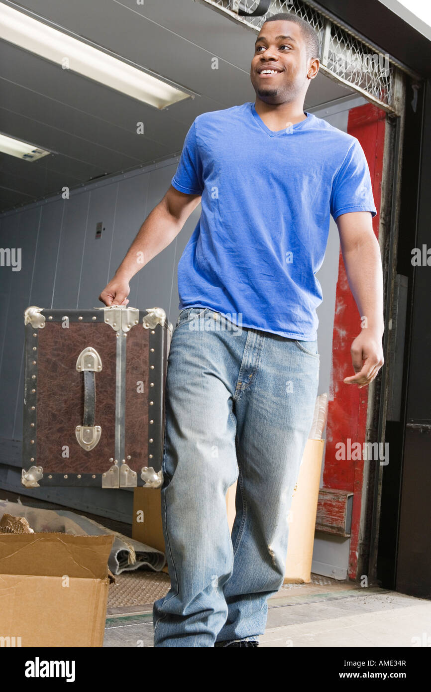 Young man carrying suitcase and smiling Stock Photo - Alamy