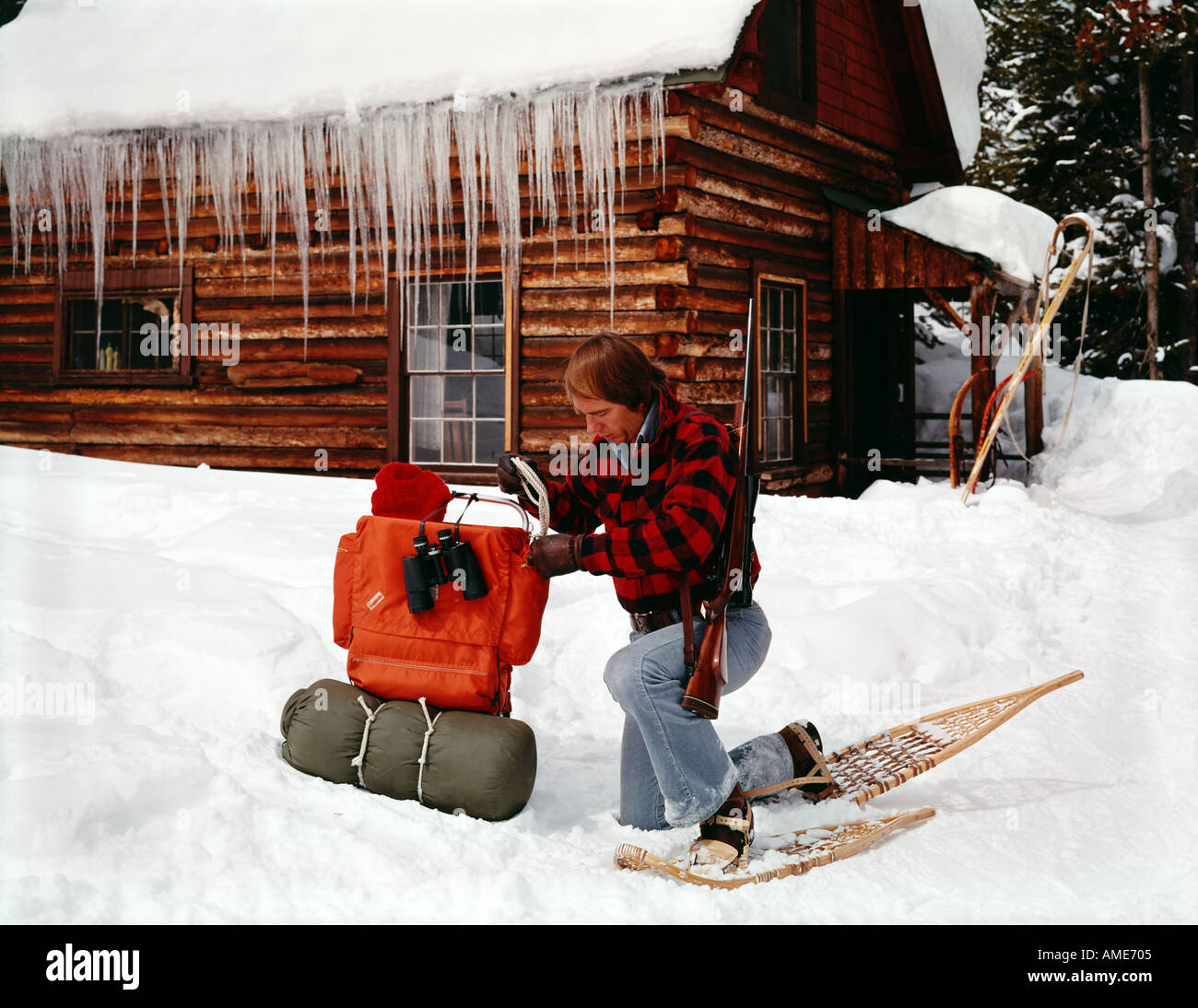 Winter hunter packing up his gear at his log cabin and preparing for a ...