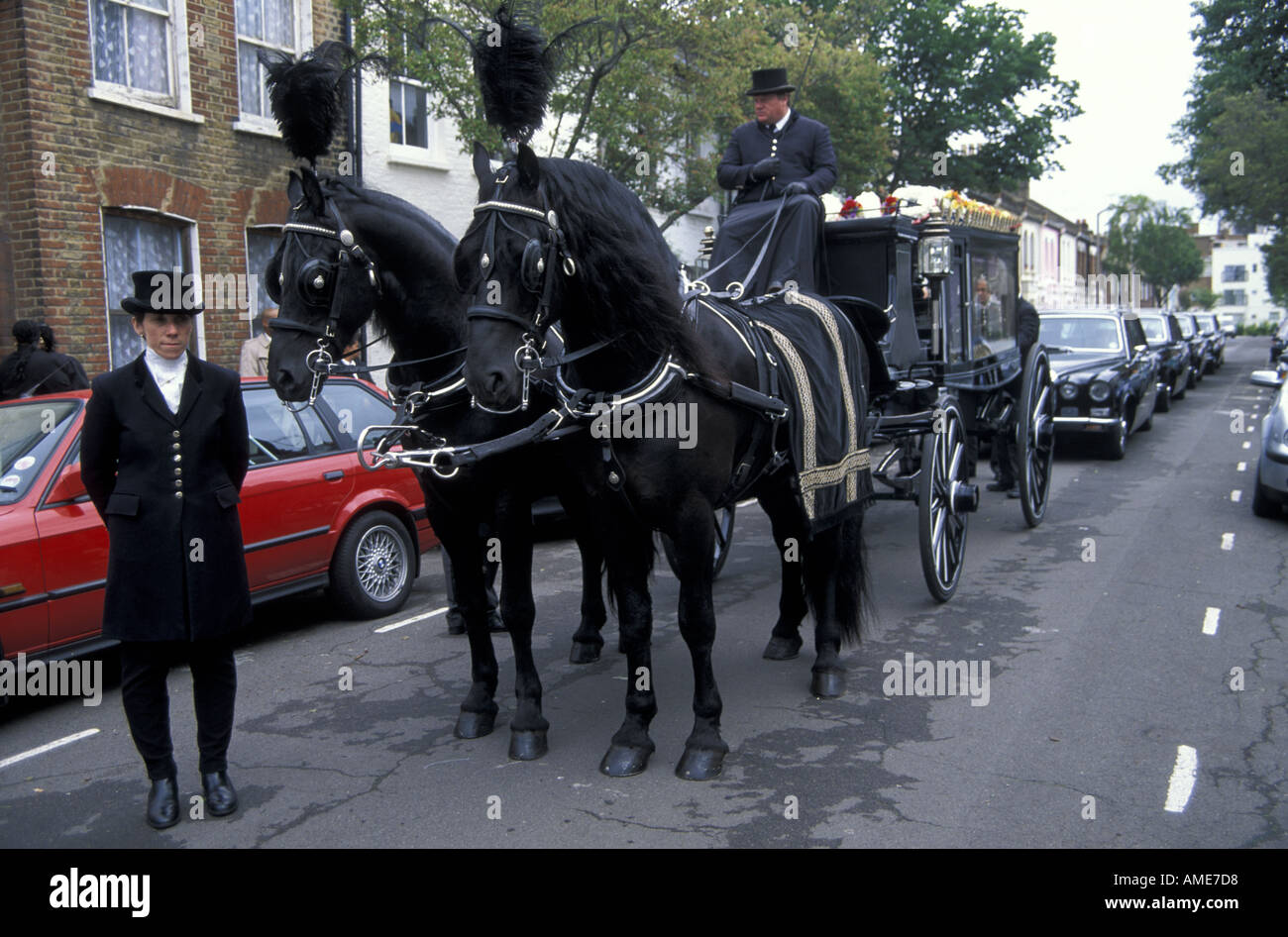 Traditional English funeral with black horses carriage and attendants ...