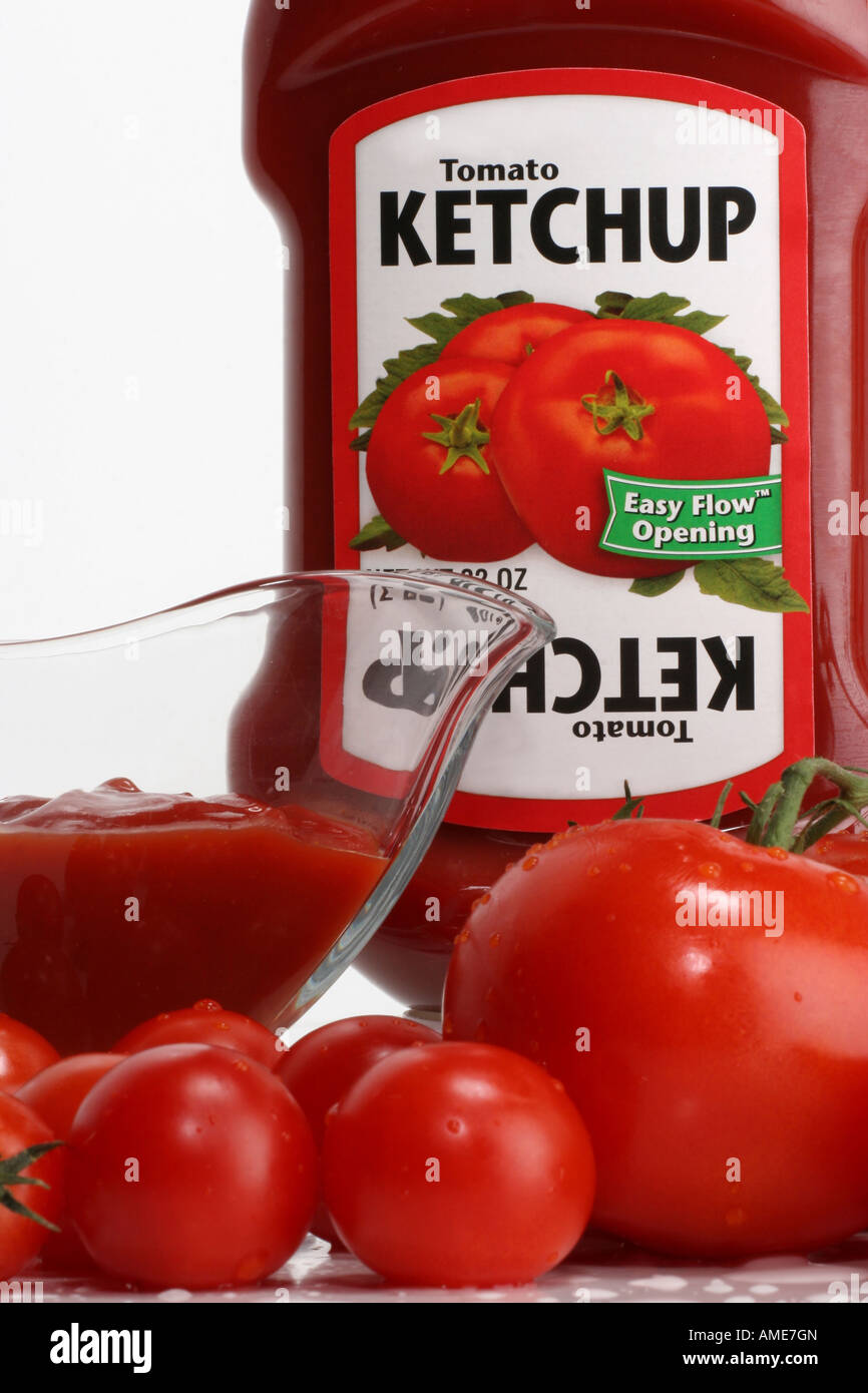 Closeup of one bottle tomato ketchup with ripe cherry tomatoes on white background nobody ...
