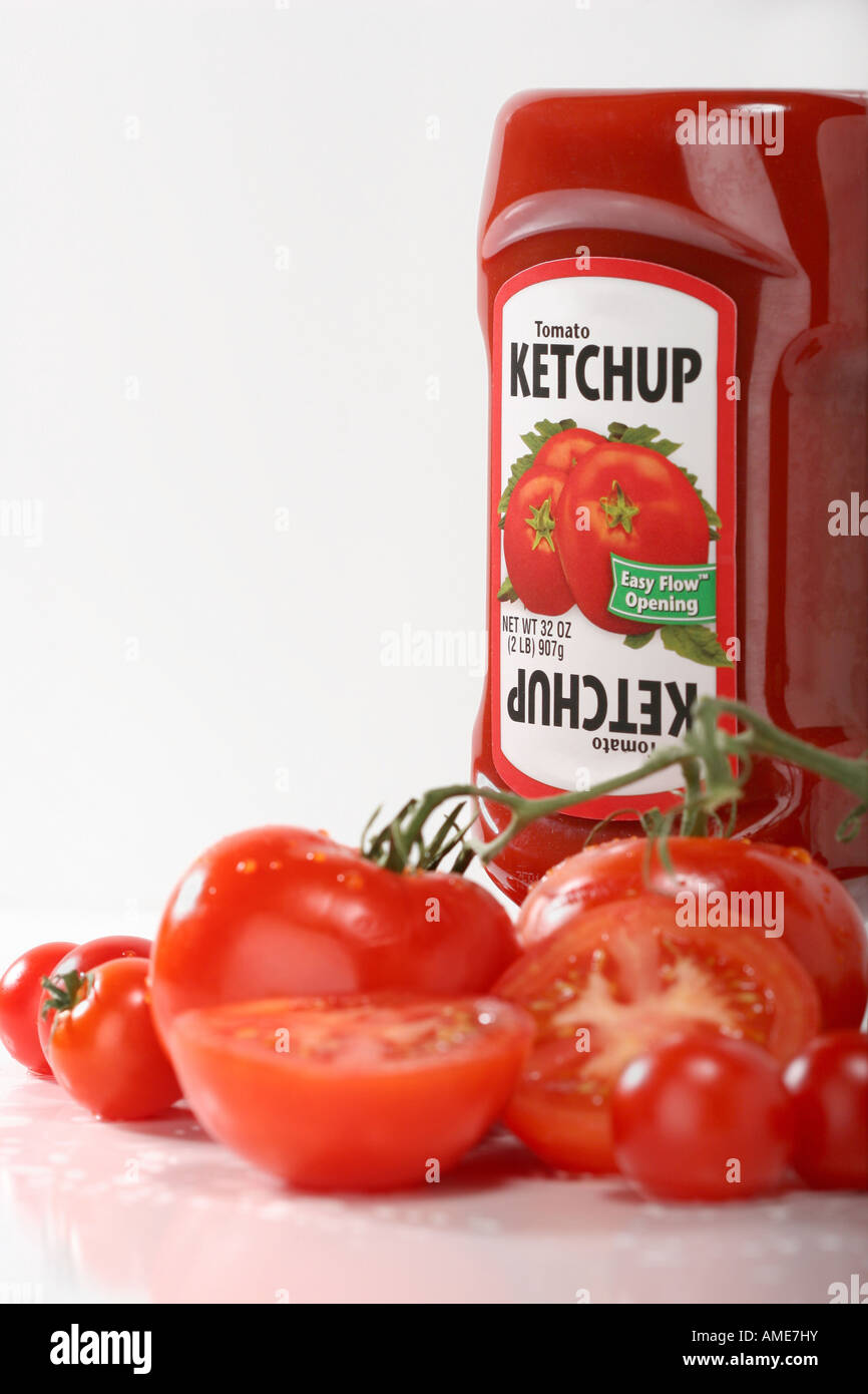 Closeup of one bottle tomato ketchup with ripe cherry tomatoes on stem white background nobody ...
