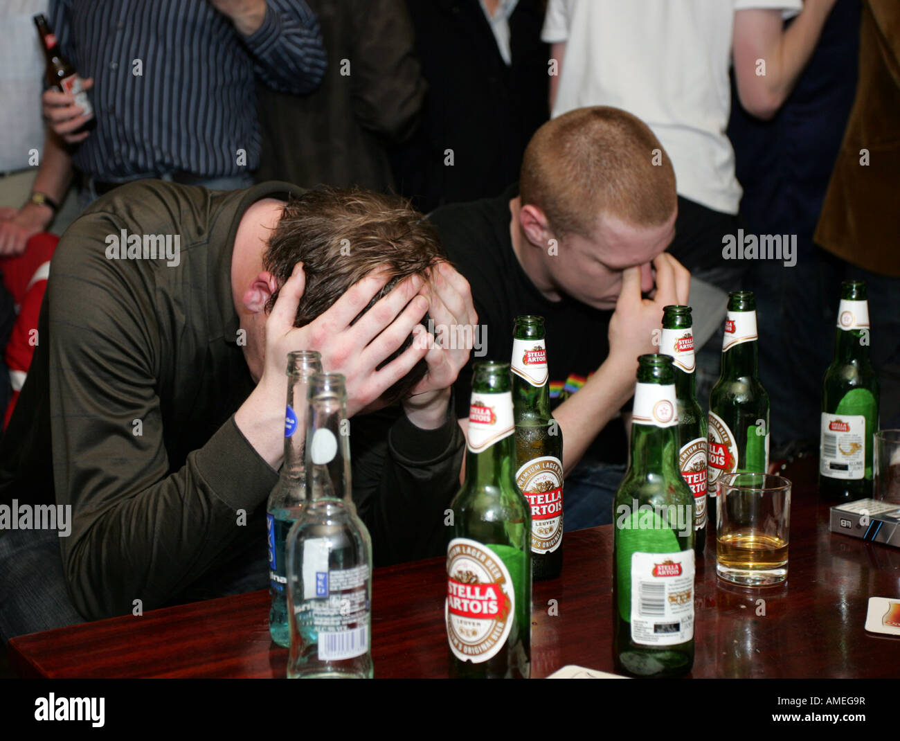 Two men inside a pub sitting at a table full of beer bottles Stock ...