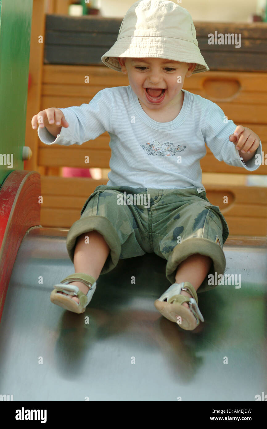 Happy child laughing as he plays on the slide in the summer sun on ...