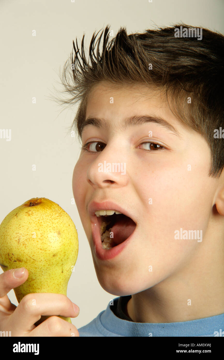 portrait of a smiling young boy biting heartily into a pear Stock Photo ...
