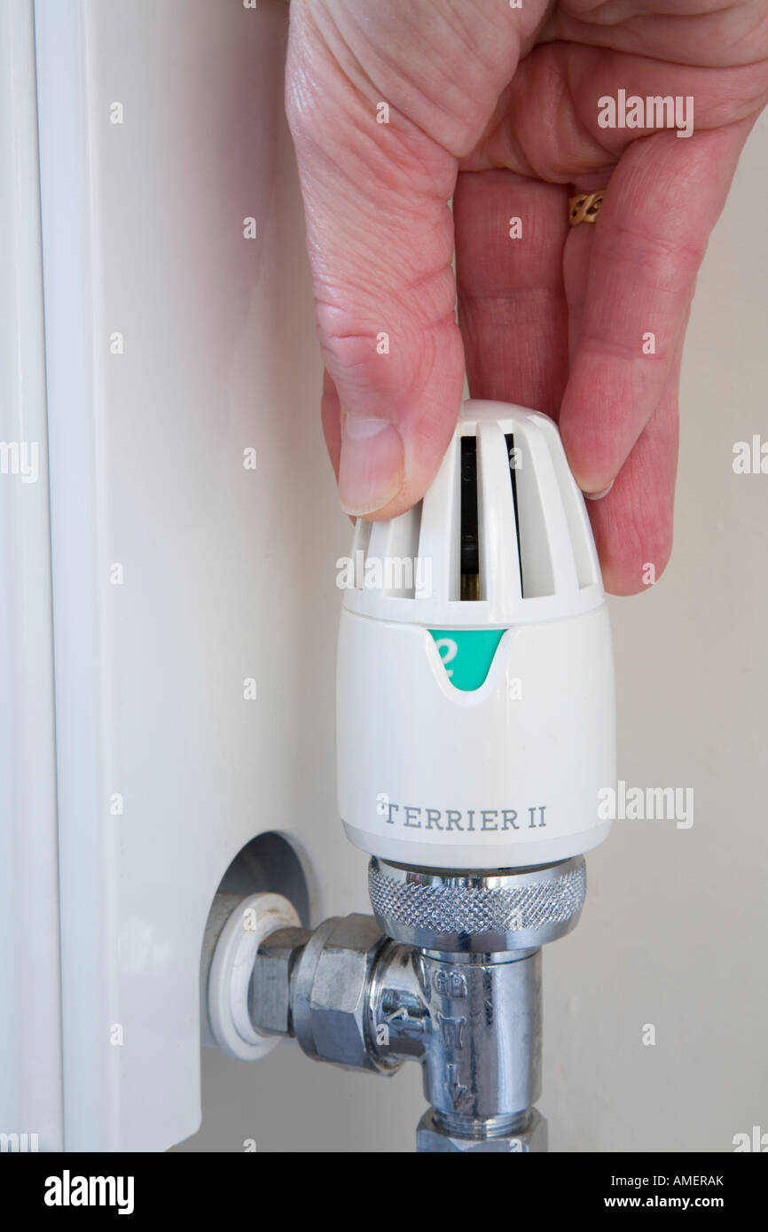 Pensioner's hand turning down household radiator thermostat control ...