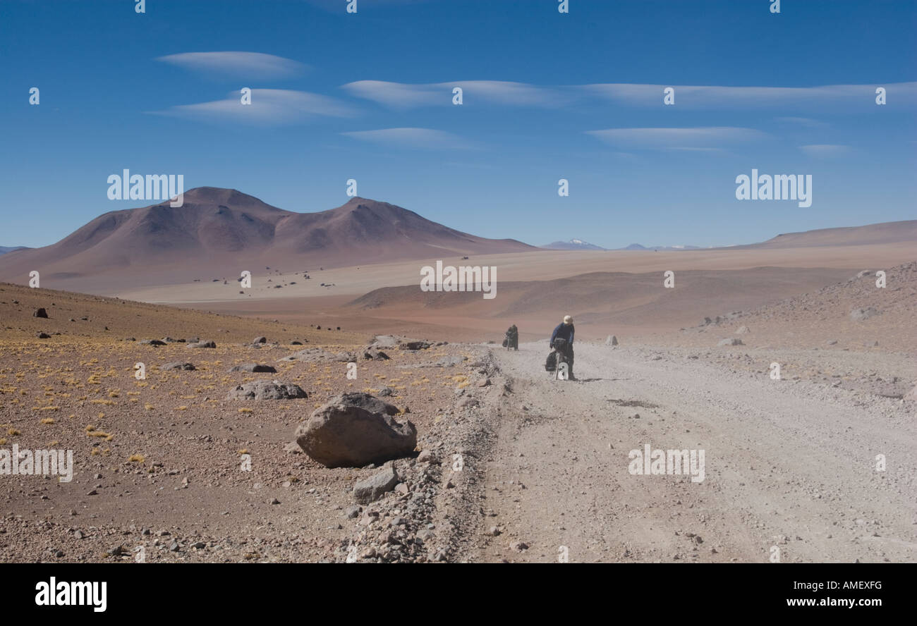 Cyclists pushing up a rough steep road into a strong headwind in south ...