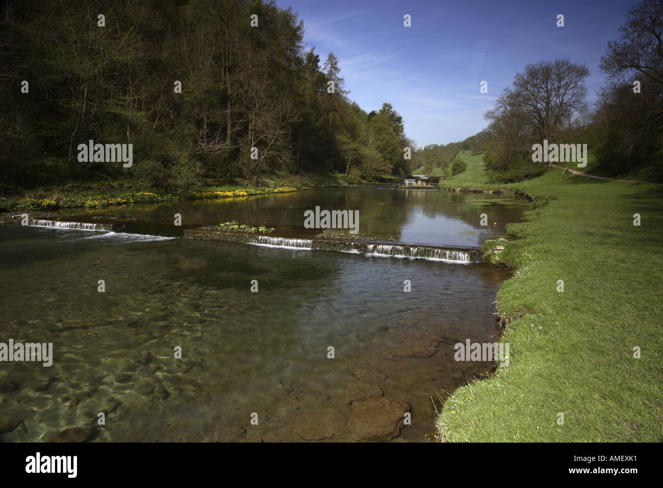 Several small waterfalls in the tree lined River Lathkill in the ...
