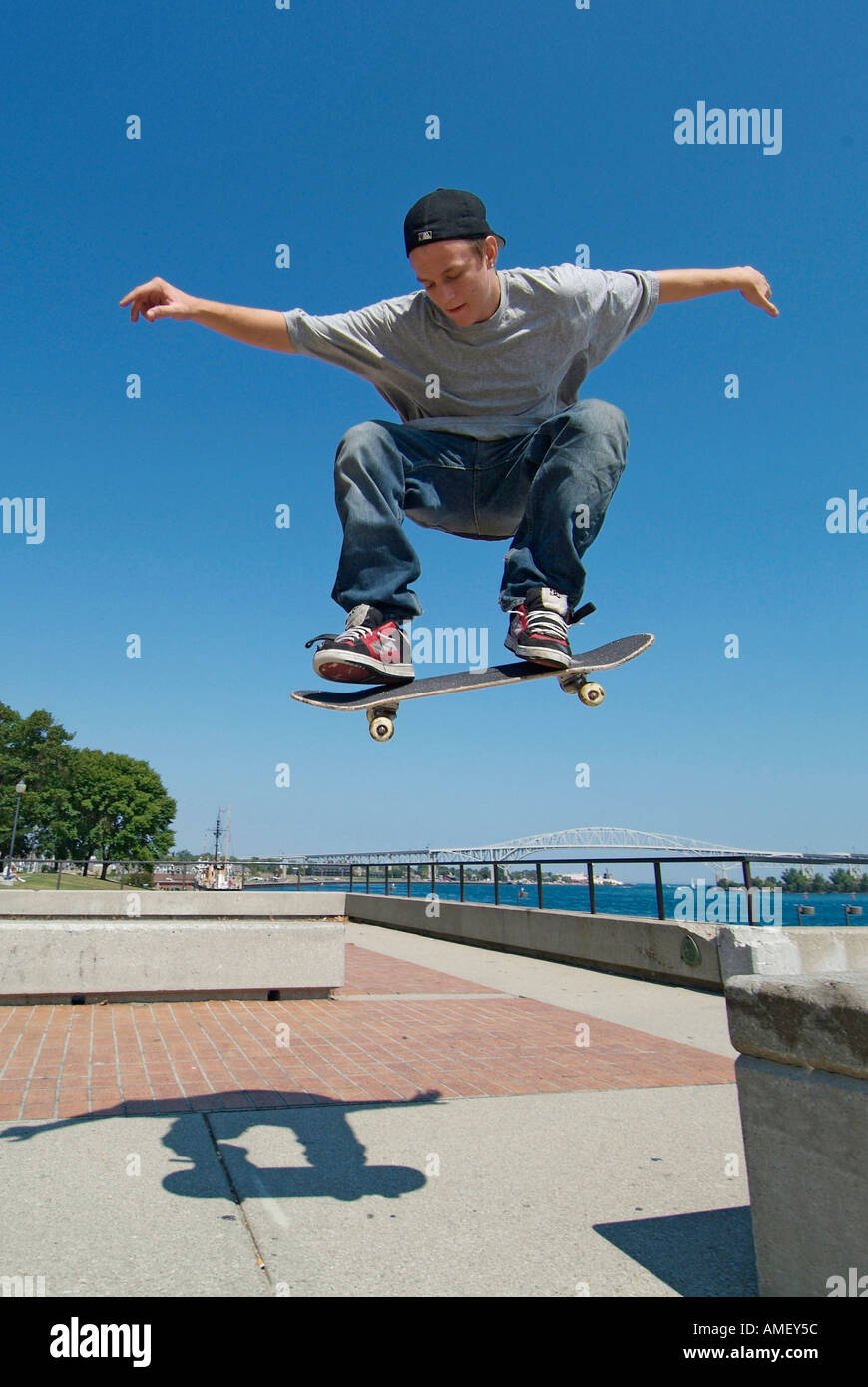Teenage males perform jumping maneuvers on a skateboard in a public ...