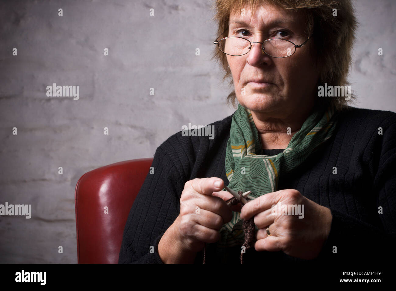 Middle age woman sitting down in a red sofa knitting (half body Stock ...