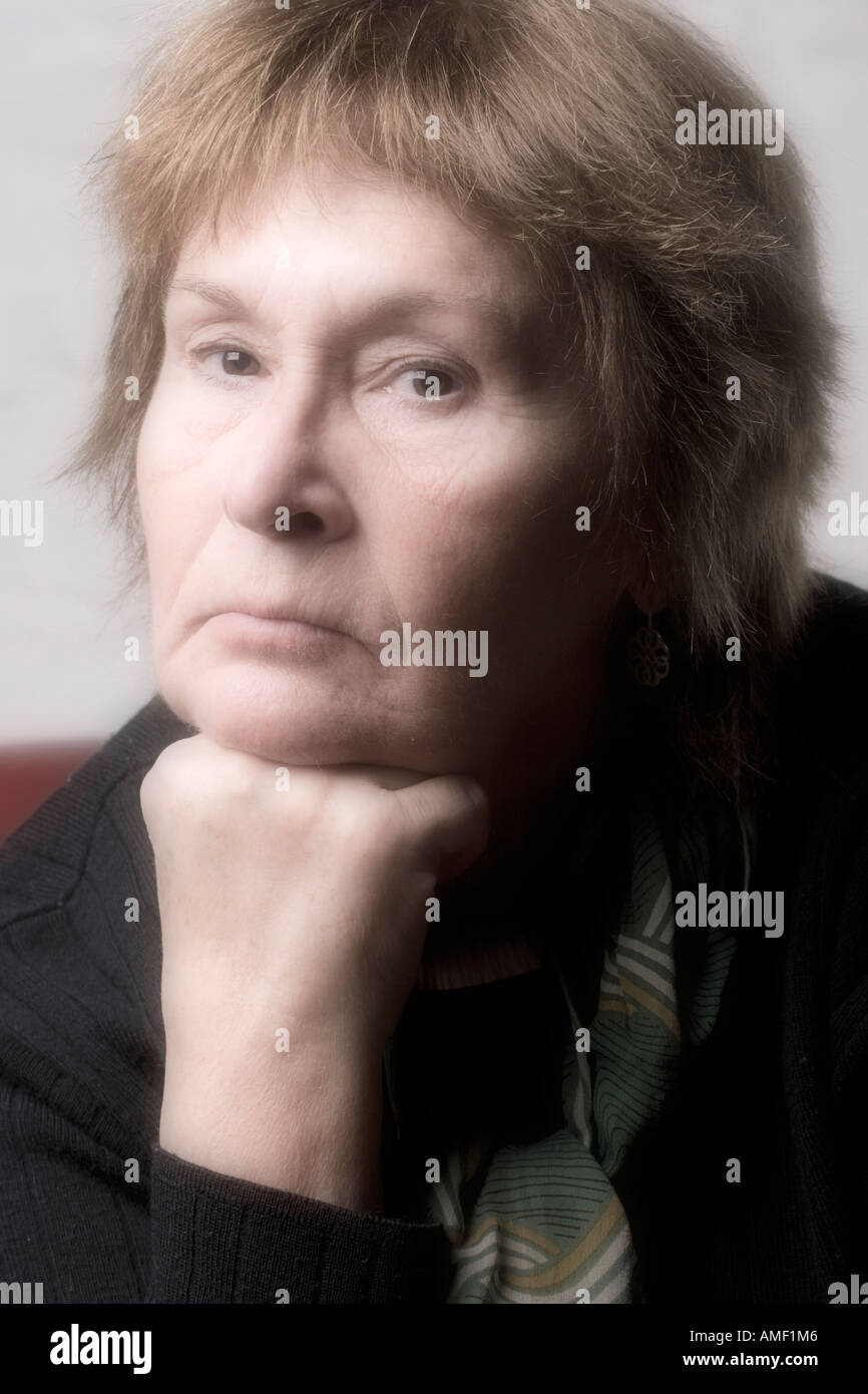 Portrait of a middle aged woman looking serious at the camera with her head resting over her ...