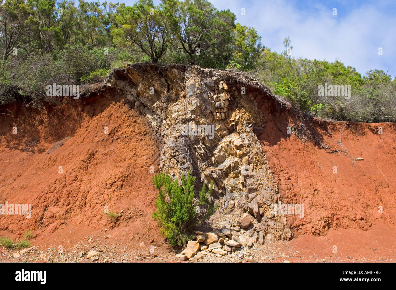 Volcanic dyke. Mass of igneous rock intruded into older red iron rich ...