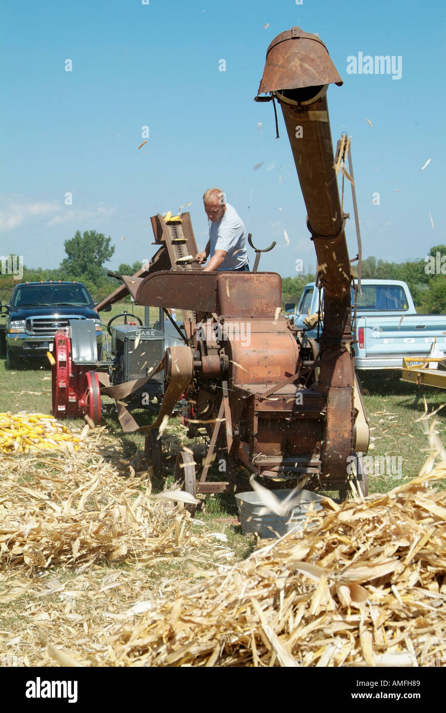 Husband and wife farmers thrash corn in a antique threshing machine ...
