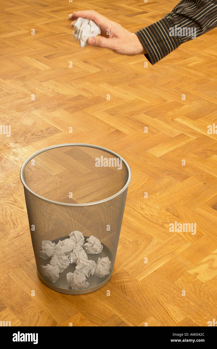mans hand throwing scrunched up crunched ball of paper into a waste ...