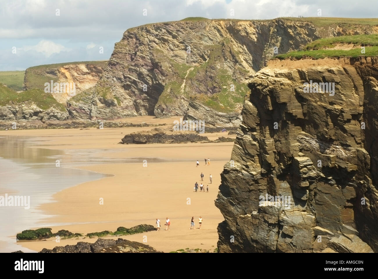 Beach goers walking on the beach at one of Newquays beaches on a hot ...