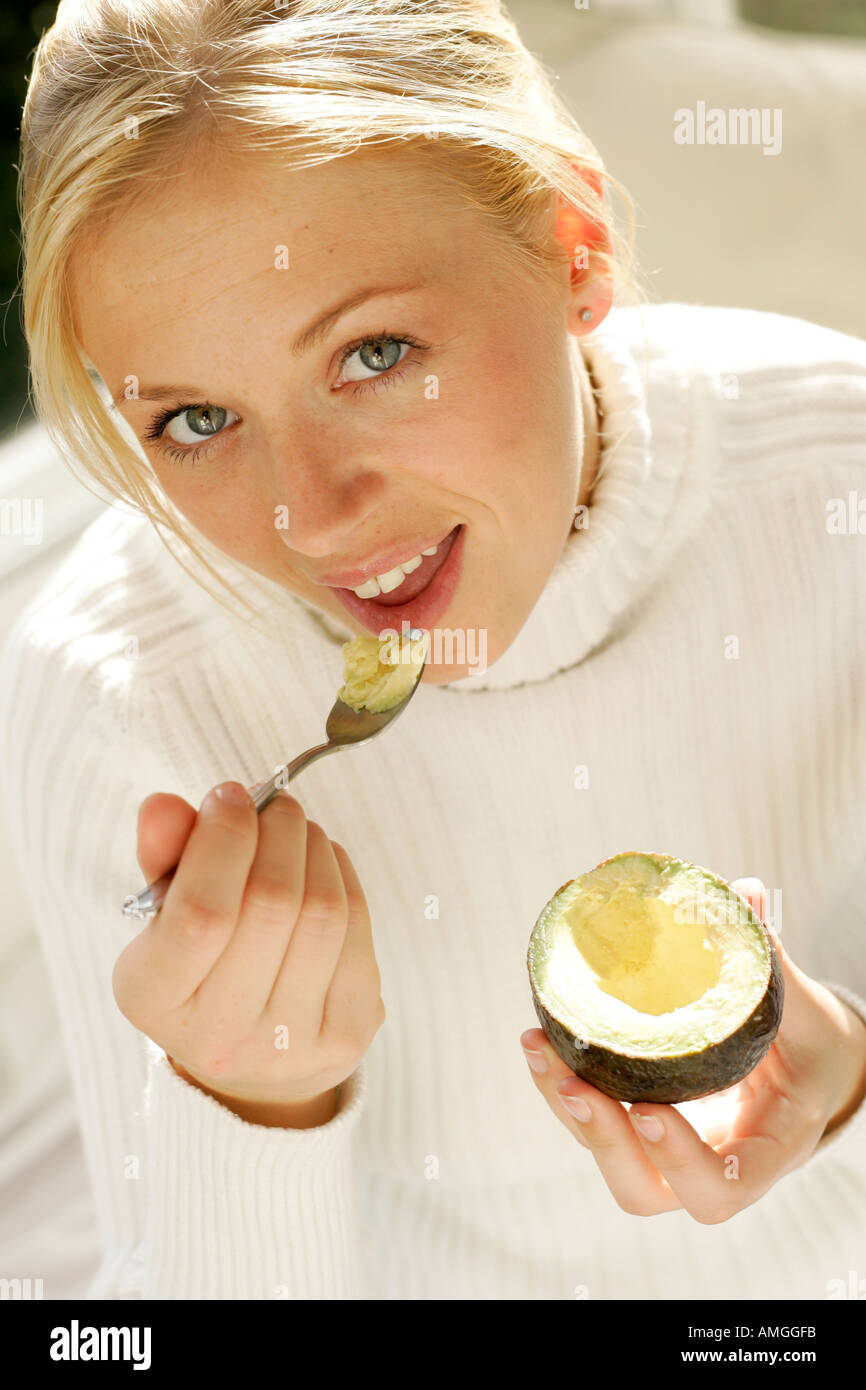 Casual portrait blonde girl eating avocado Stock Photo - Alamy