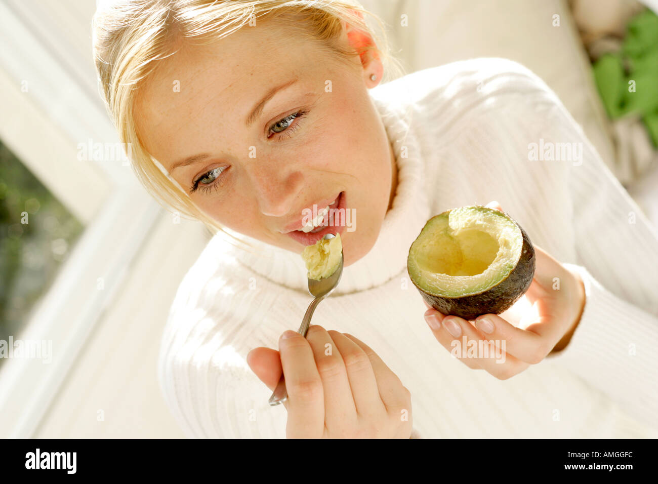 Casual portrait blonde girl eating avocado Stock Photo - Alamy
