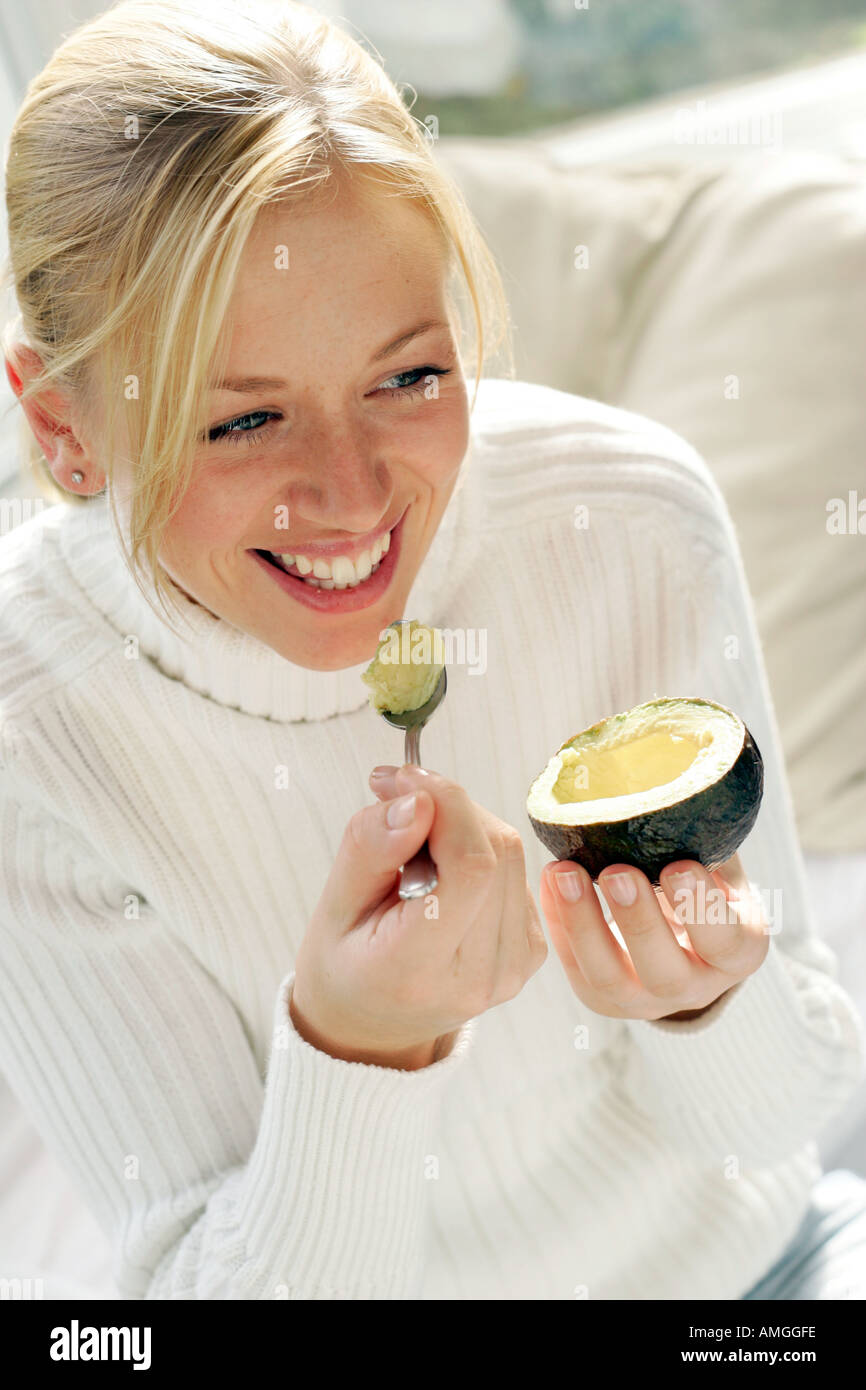 Casual portrait blonde girl eating avocado Stock Photo - Alamy