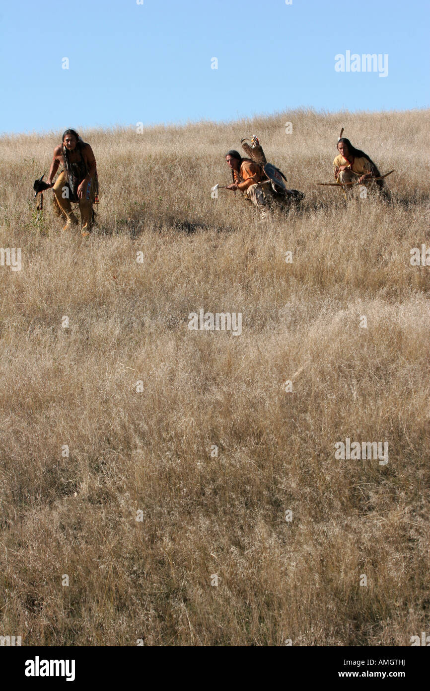 Three Native American Indian men crouching in the dead grasses hunting ...