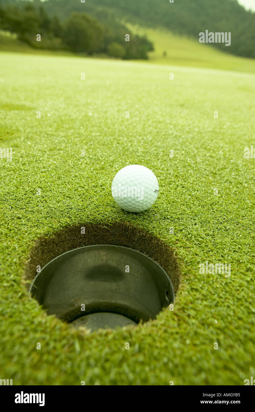 A golf ball and a hole Stock Photo - Alamy