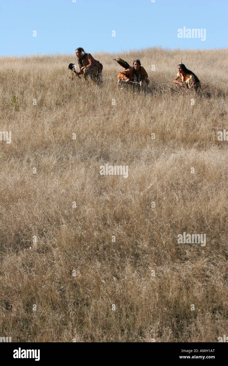 Three Native American Indian men crouching in the dead grasses hunting ...