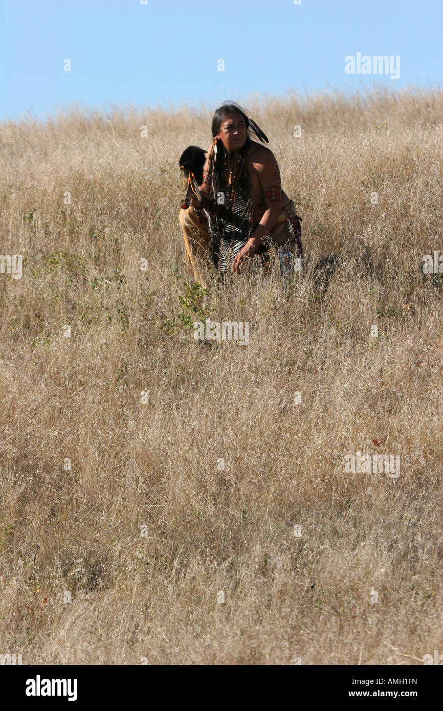 A Native American Indian man crouching in the dead grasses hunting game ...