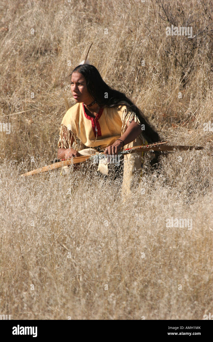A Native American Indian boy crouching in the dead grasses hunting game ...