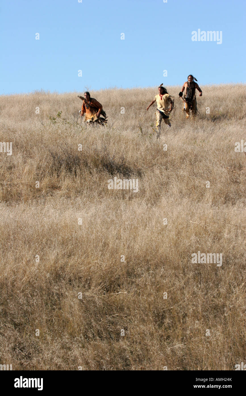Three Native American Indian men running downhill in the dead grasses ...