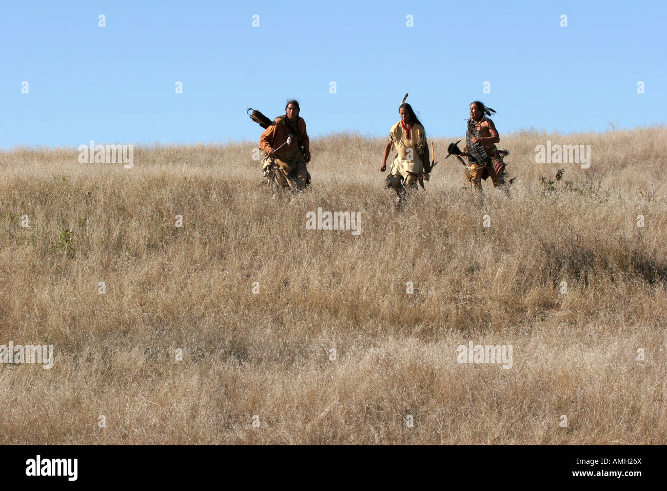 Three Native American Indian men running downhill in the dead grasses ...