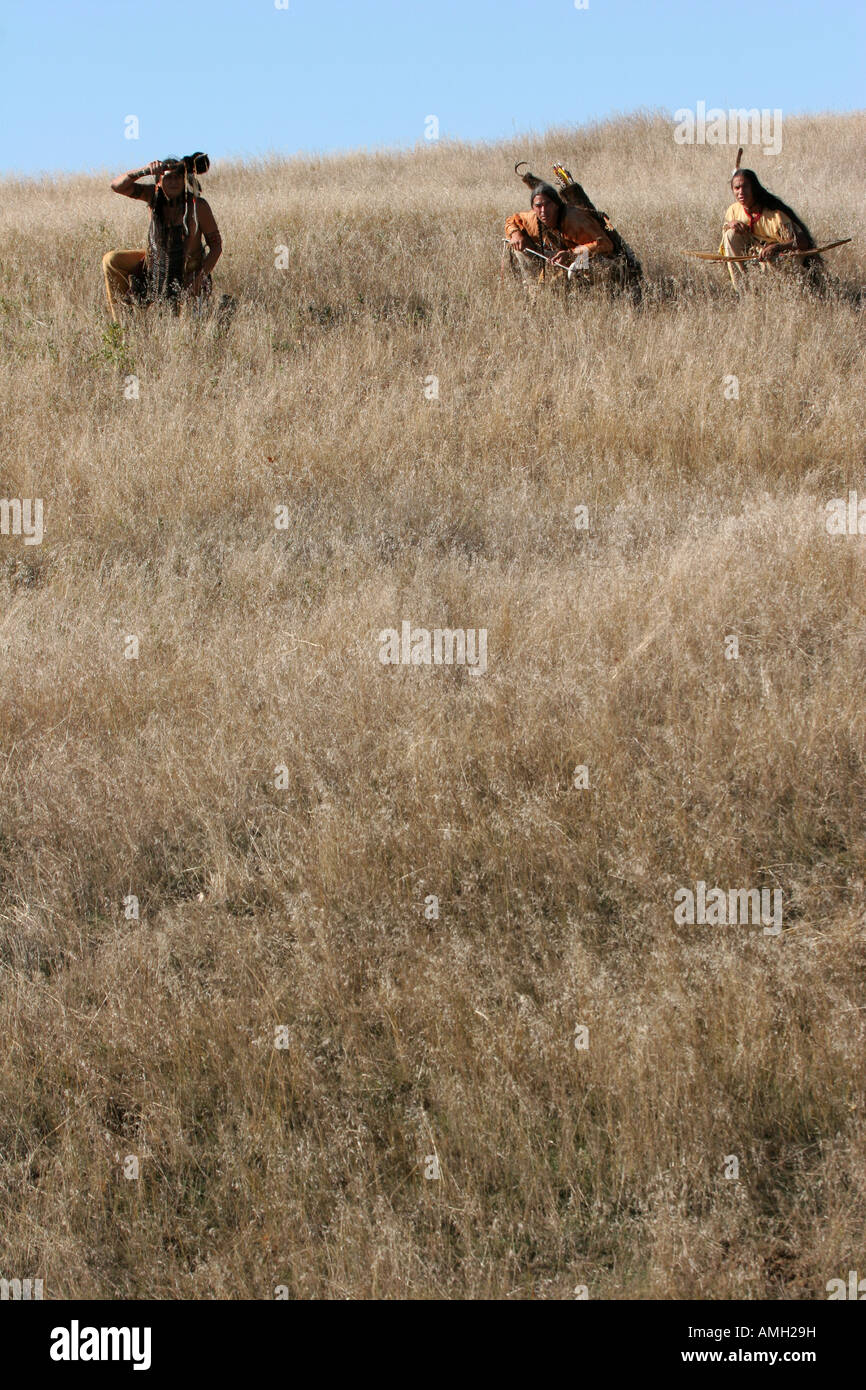 Three Native American Indian men crouching in the dead grasses hunting ...