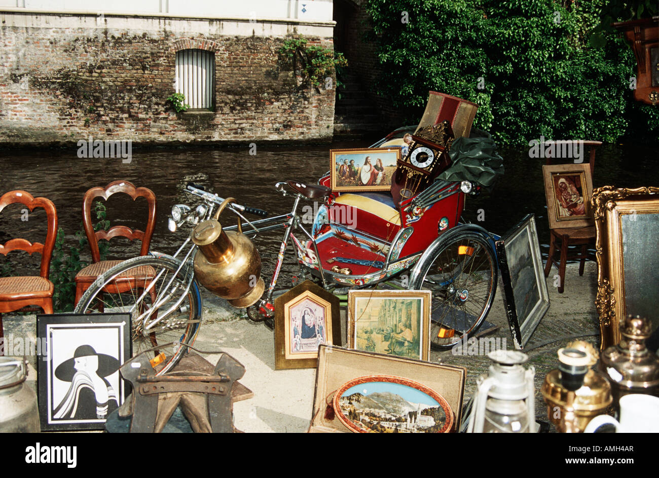 Antiques for sale in a flea market on a pavement beside a canal, Bruges ...