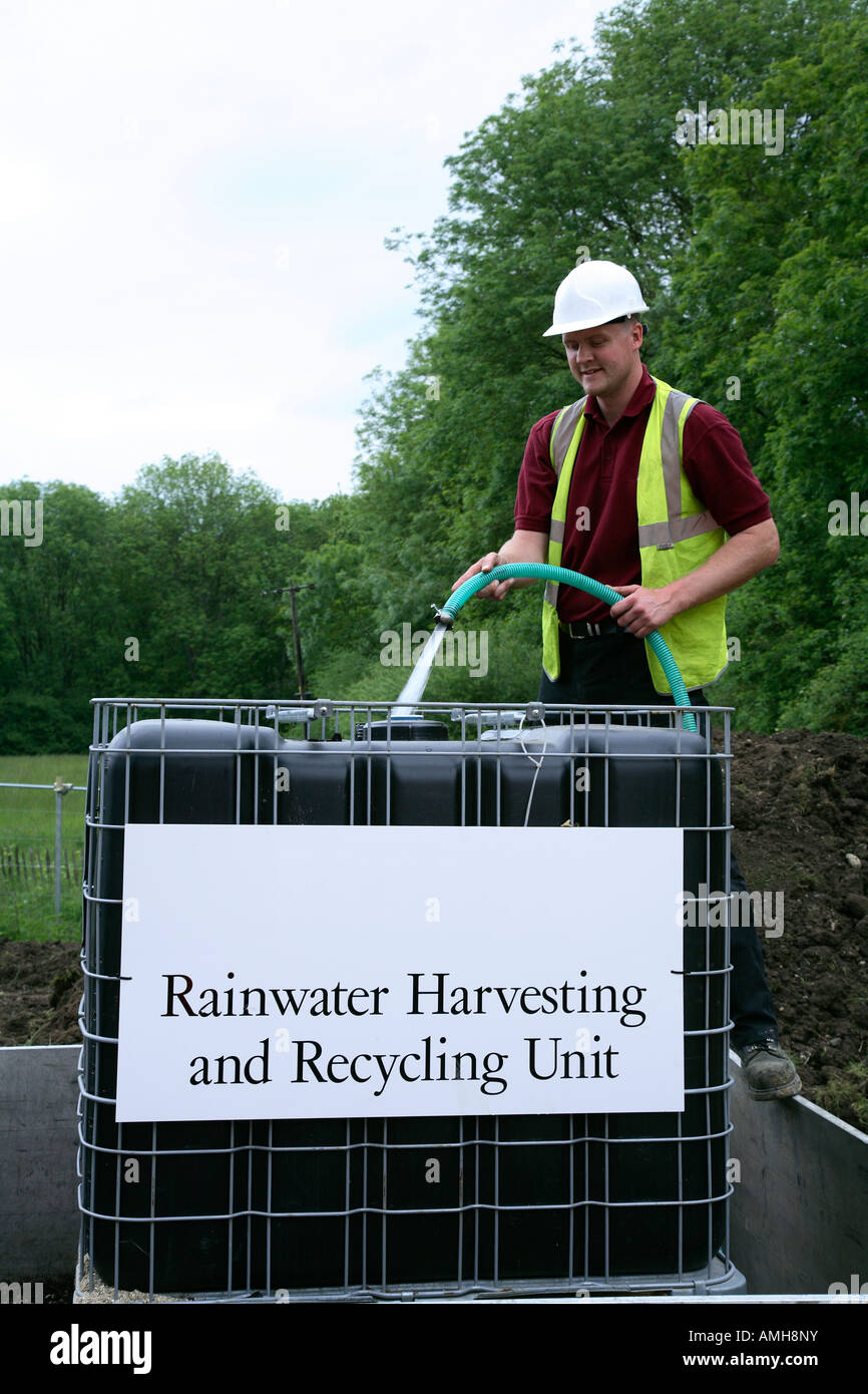 Workman filling mobile water storage tank from rainwater recycling ...