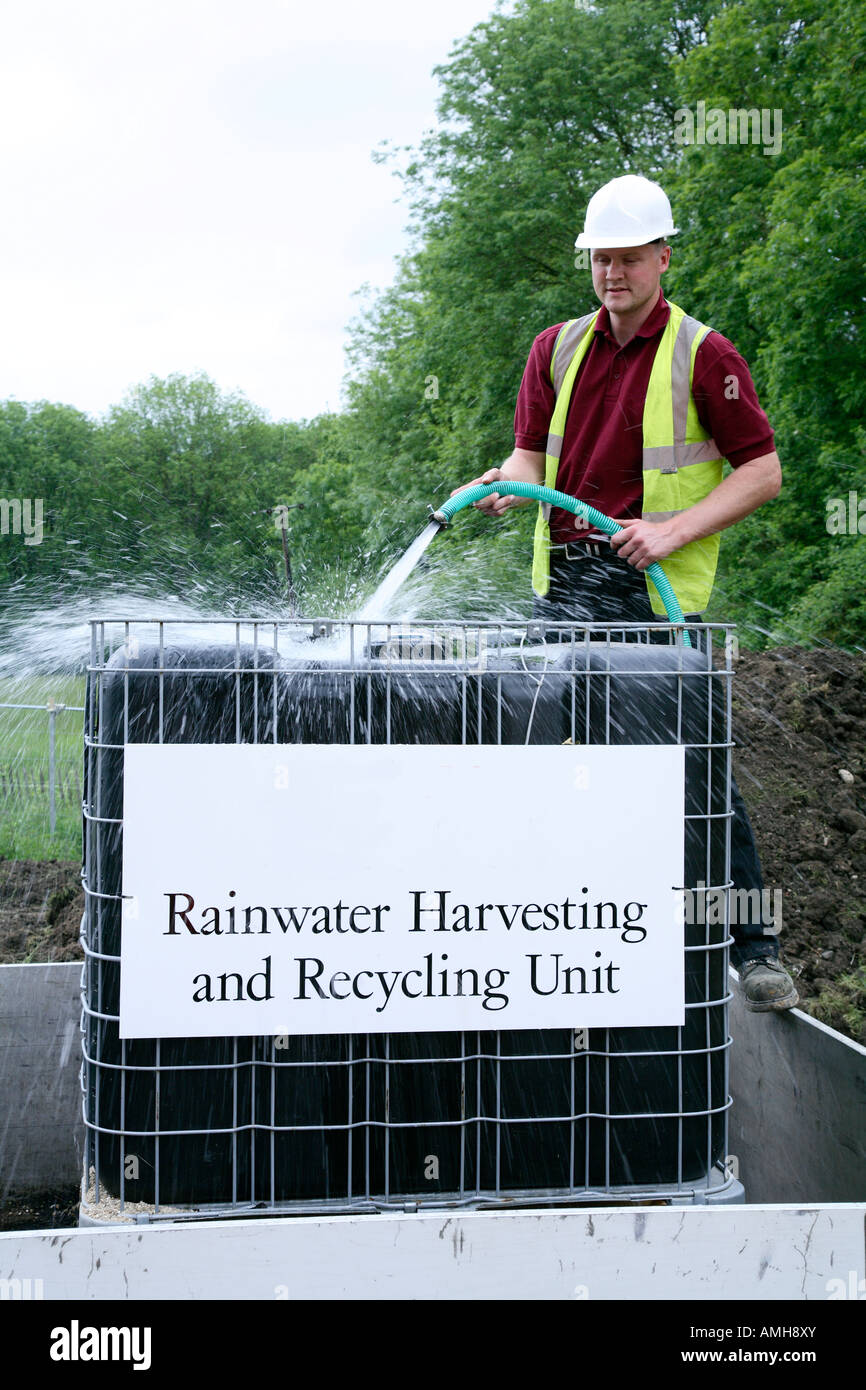 Workman filling mobile water storage tank from rainwater recycling ...