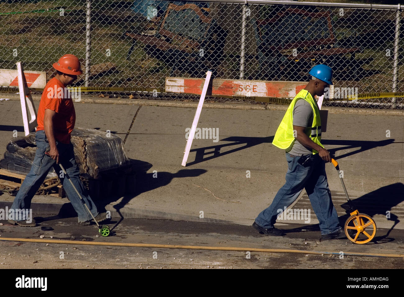 Construction workers measure distance using wheeled measuring devices ...
