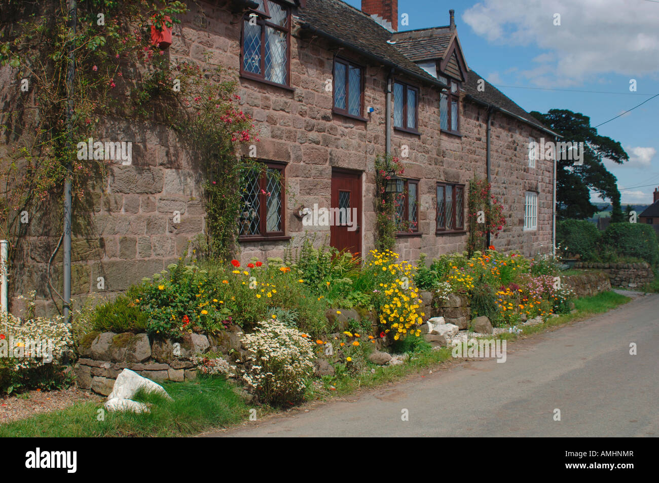 An Assortment Of Different Coloured Flowers In Front Of A Stone Cottage ...