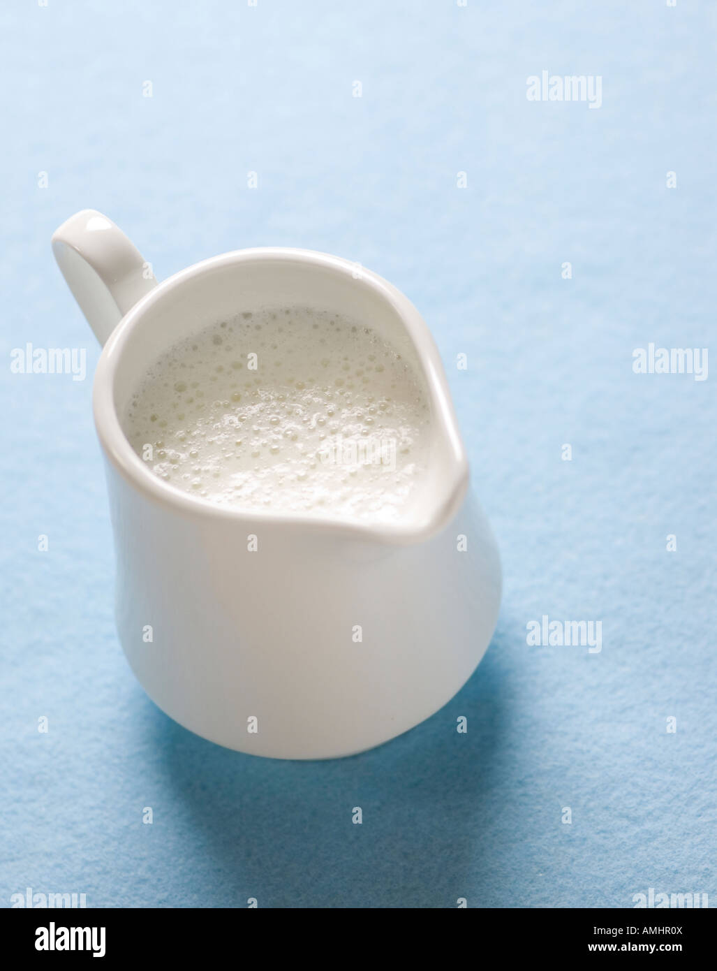 a small pitcher of fresh milk on blue background Stock Photo - Alamy
